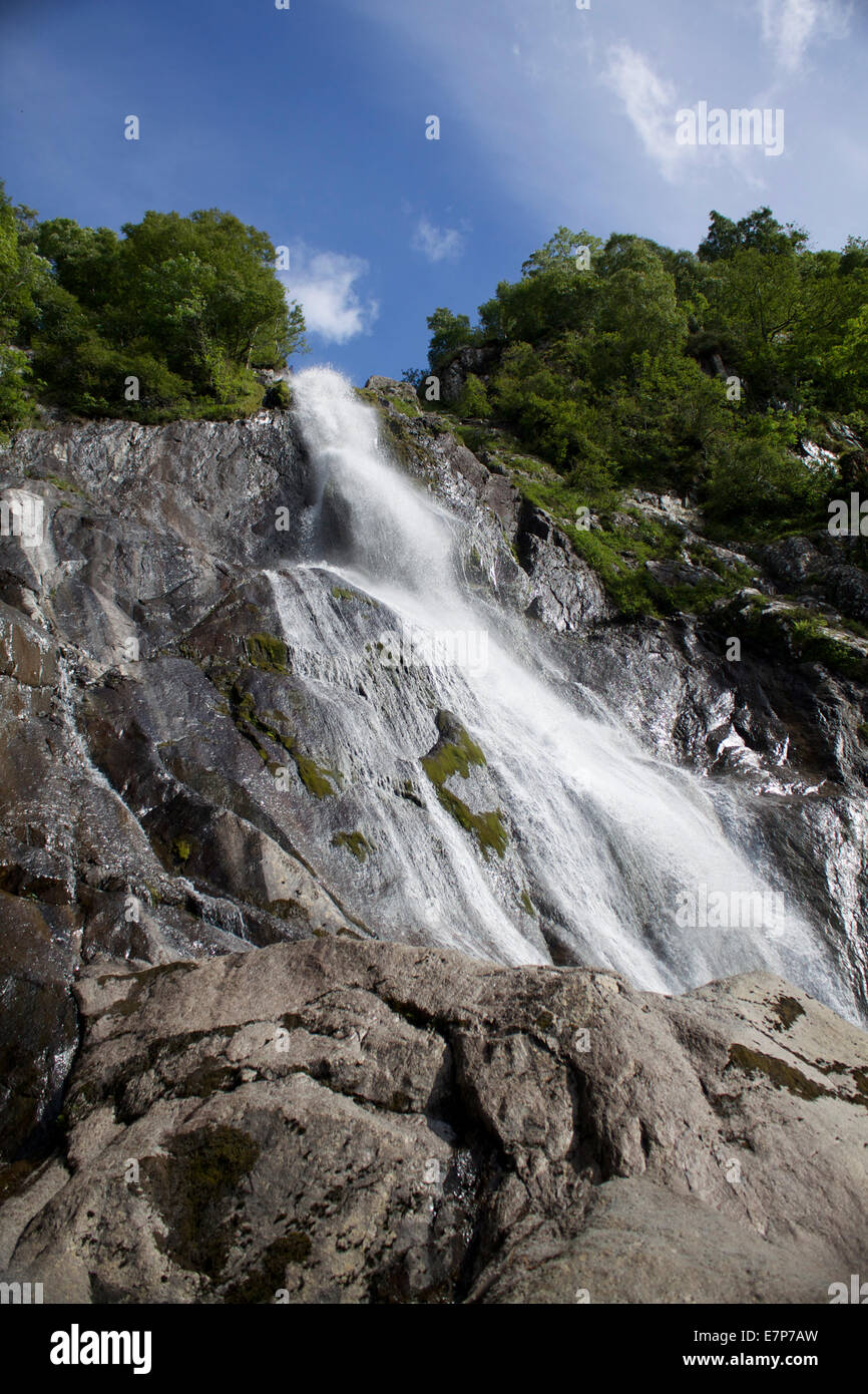 Waterfall over rocks between trees with sky in the background Stock ...