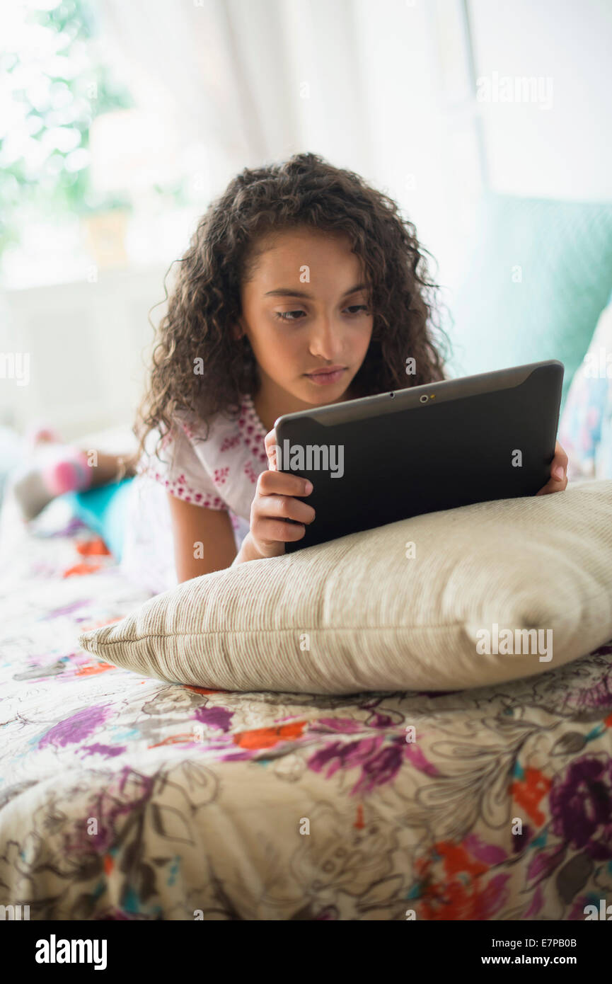 Girl (8-9) using digital tablet on bed Stock Photo - Alamy