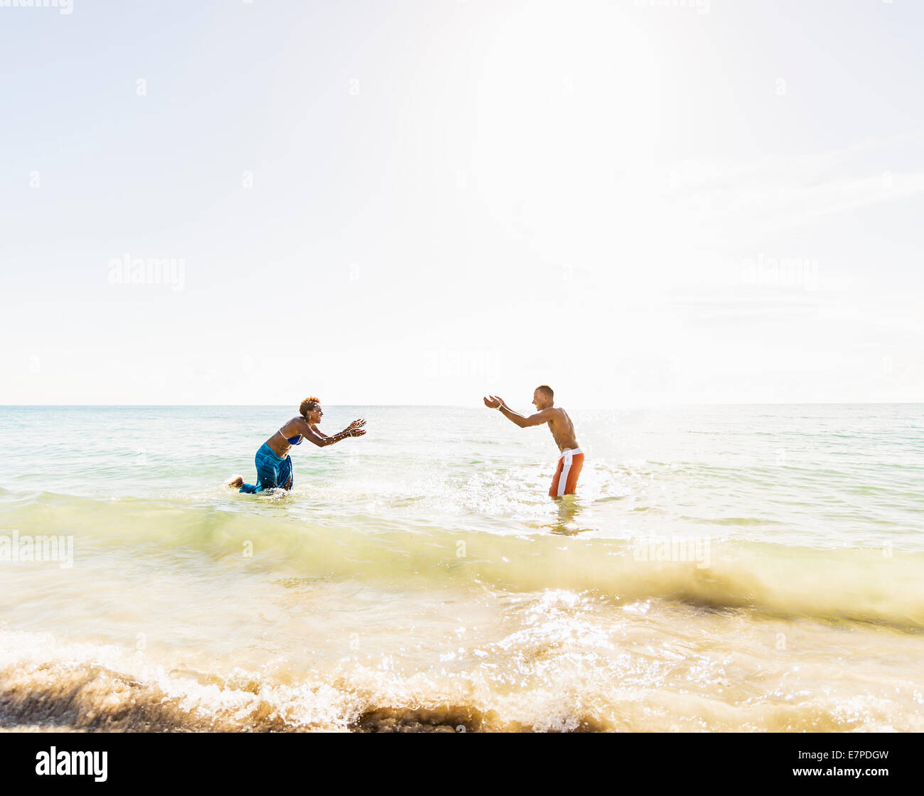 Man and woman splashing water on beach Stock Photo - Alamy