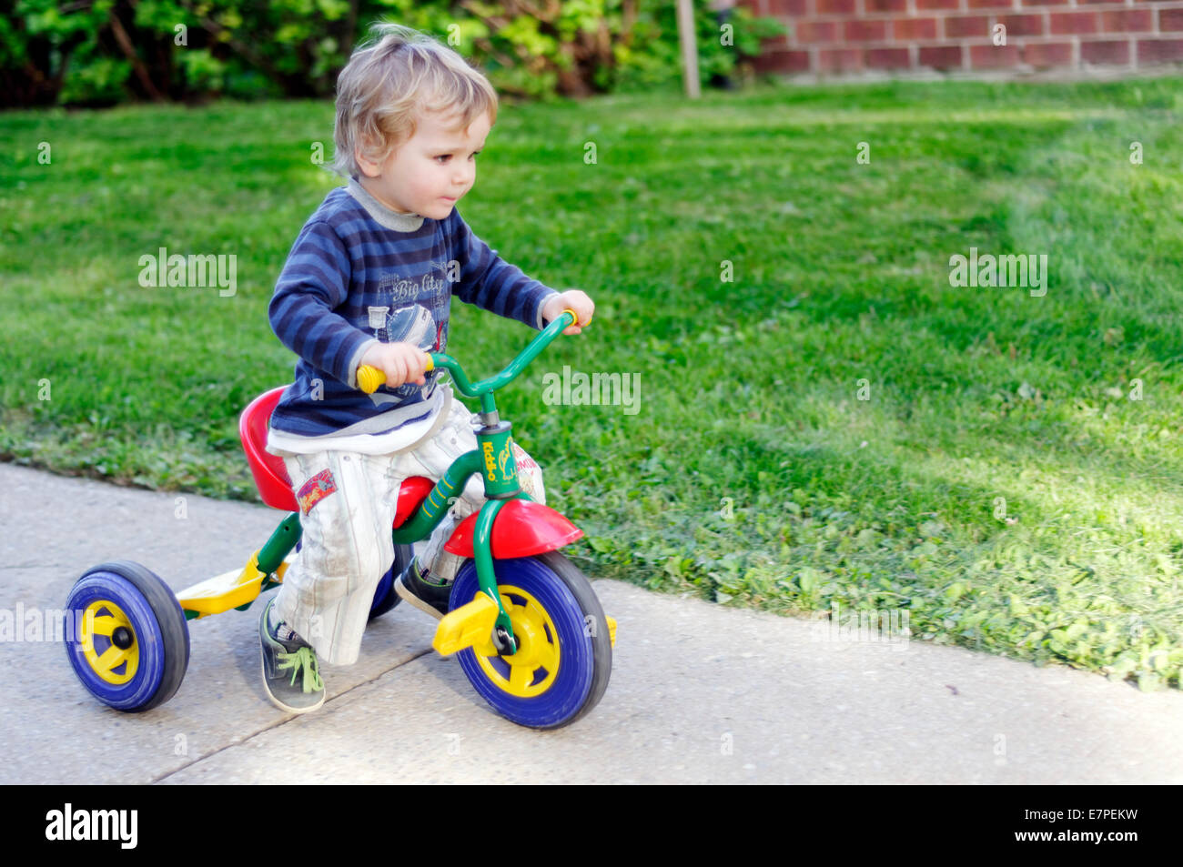 A young boy (2 1/2 yrs) riding a tricycle outside Stock Photo - Alamy