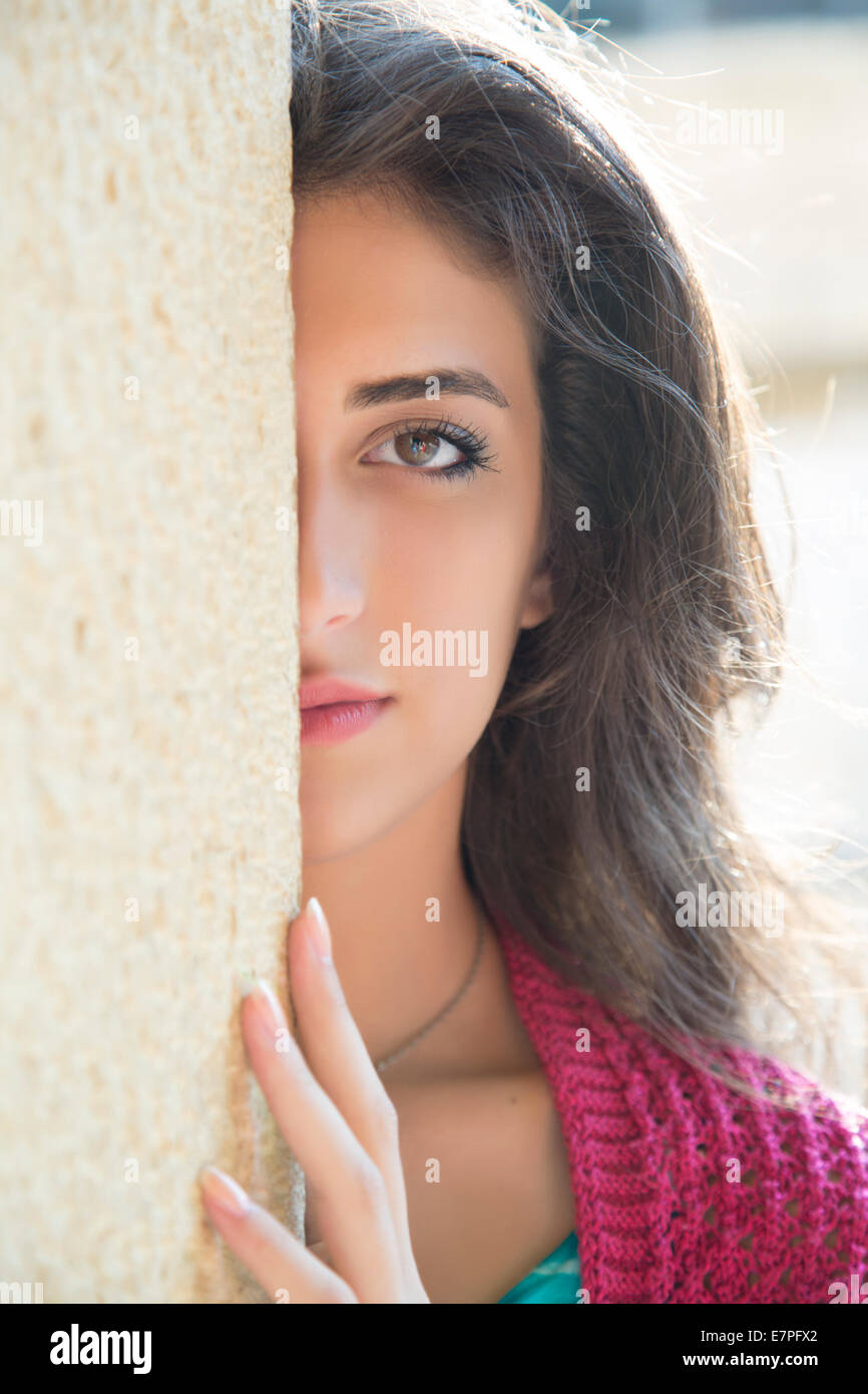 Young woman hiding behind a wall Stock Photo - Alamy