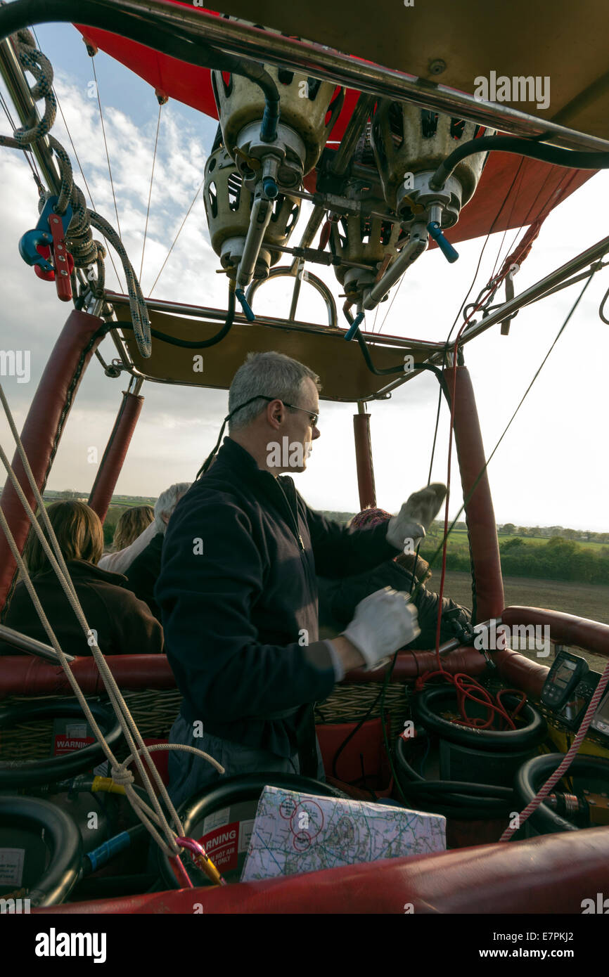 Pilot steering a hot air balloon with passengers enjoying the view ...