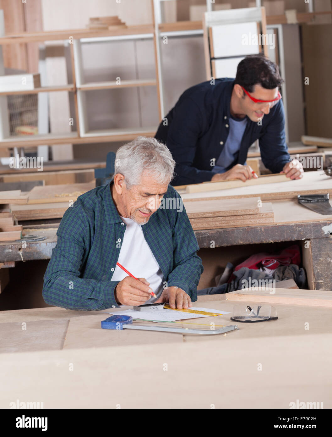 Carpenter Working On Blueprint At Workshop Stock Photo - Alamy