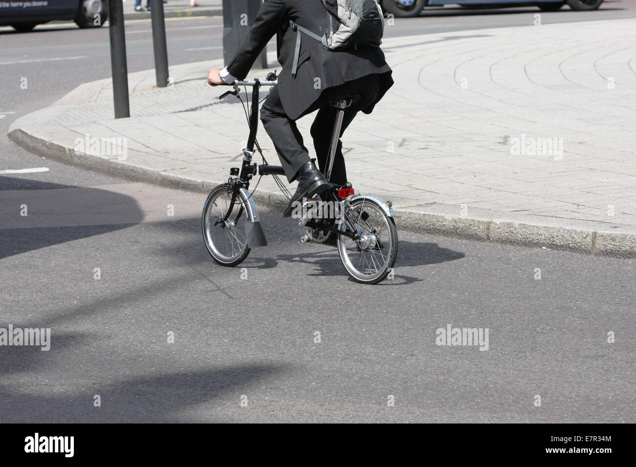 A cyclist wearing a suit and riding his folding cycle around the ...