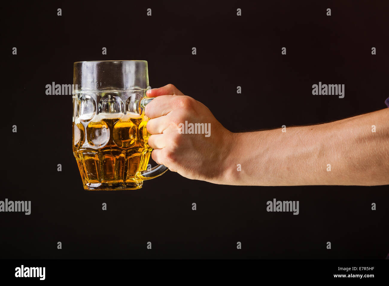 Male hand holding mug of beer dark background Stock Photo - Alamy