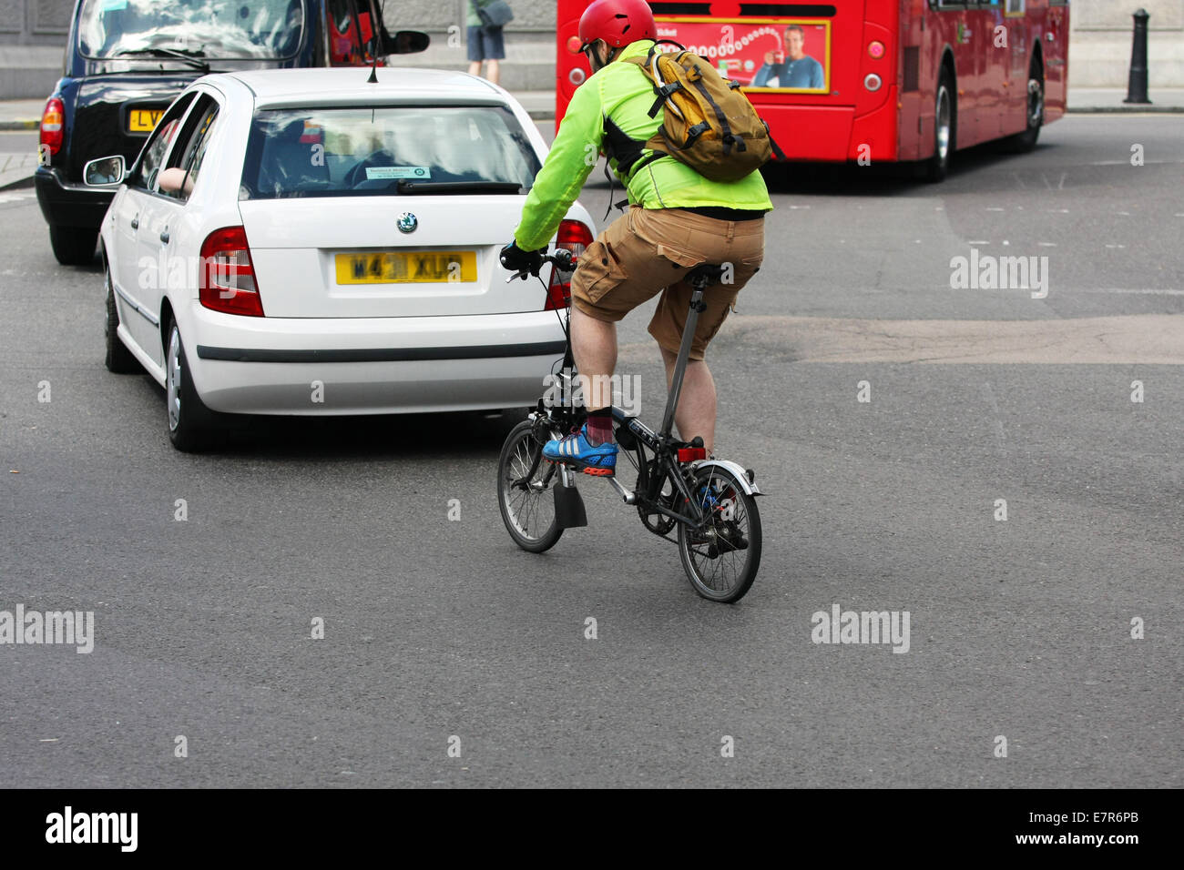 A cyclist on a folding cycle riding behind traffic on a roundabout in ...