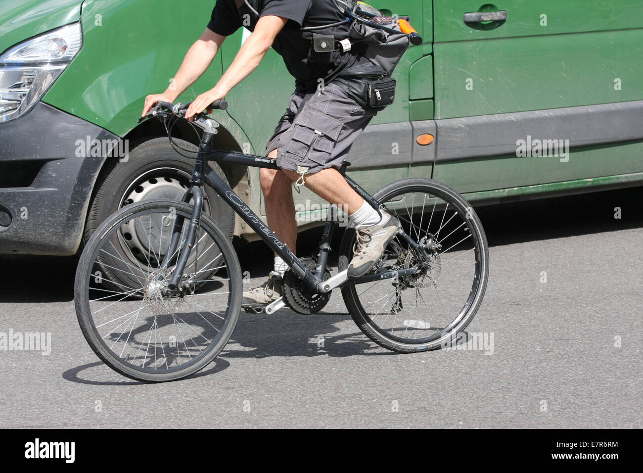 A cyclist traveling alongside a green van in London Stock Photo - Alamy