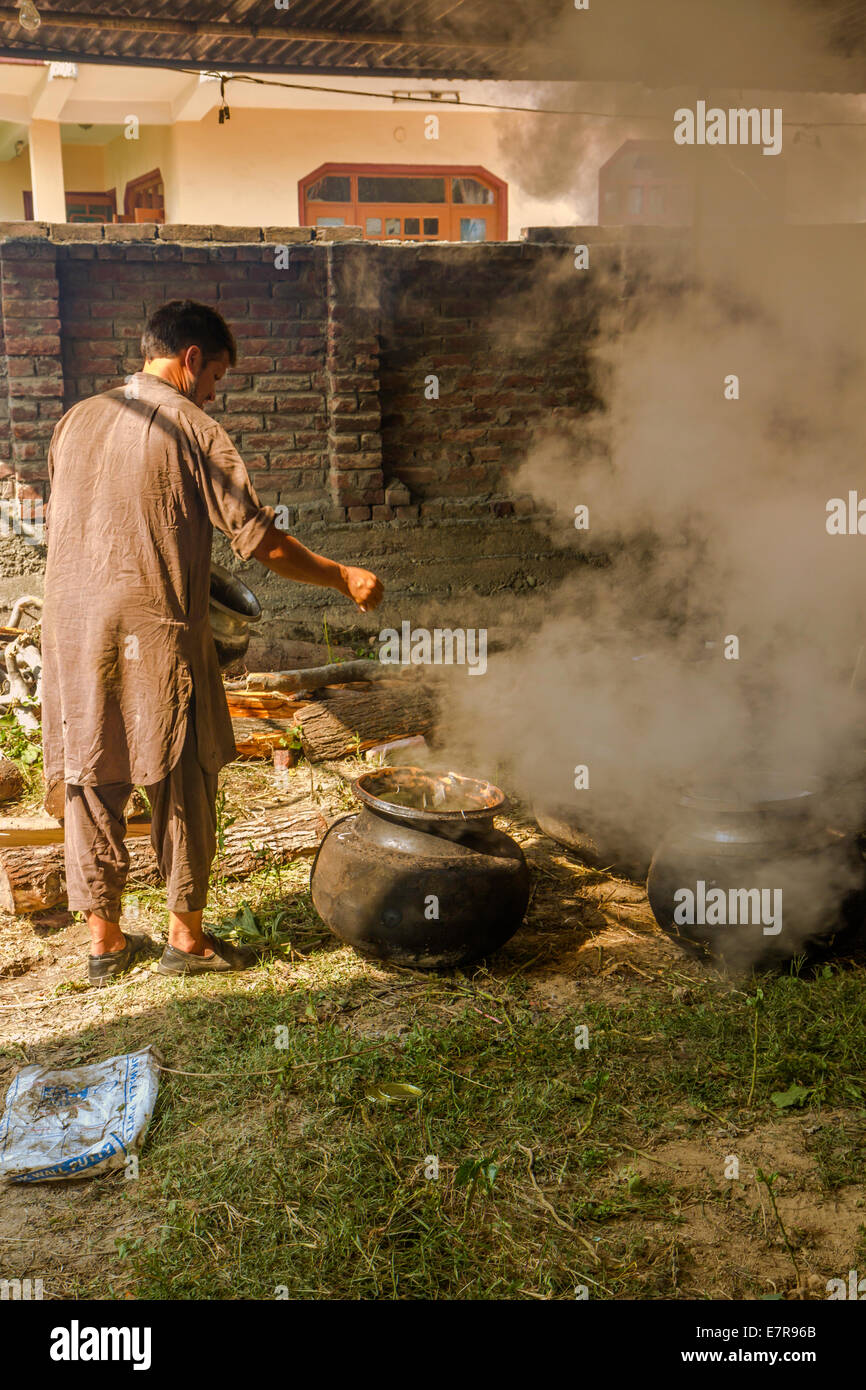 Head chef adds salt to the cooking pot; over an open log fire Stock ...