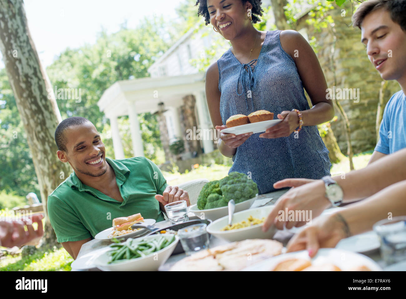 A family gathering, men, women and children around a table in a garden ...