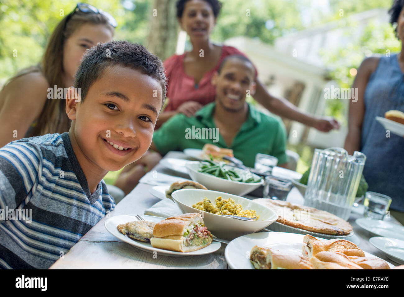A family gathering, men, women and children around a table in a garden ...