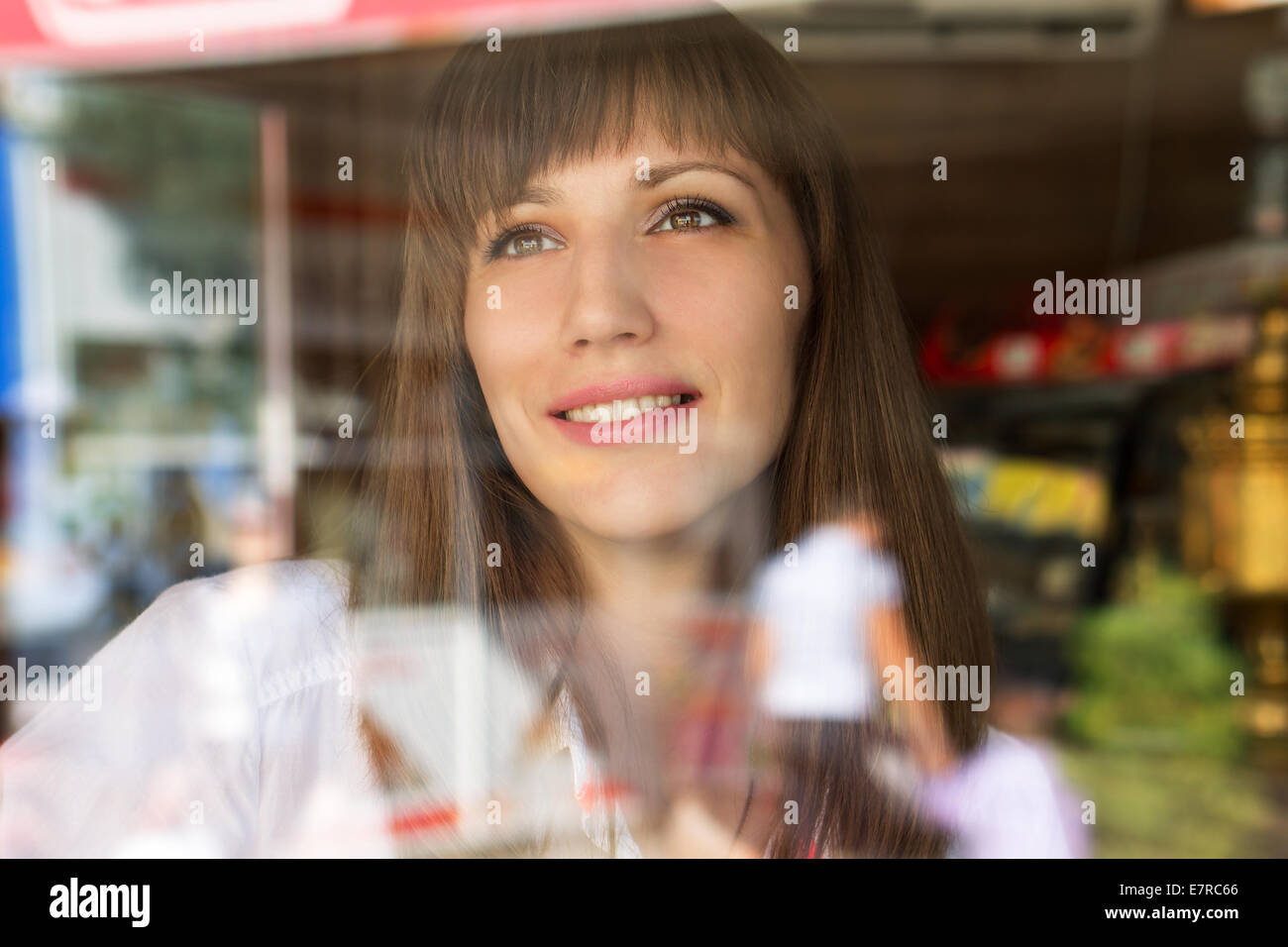 Beautiful smiling girl drinking coffee and looking out through windowin ...