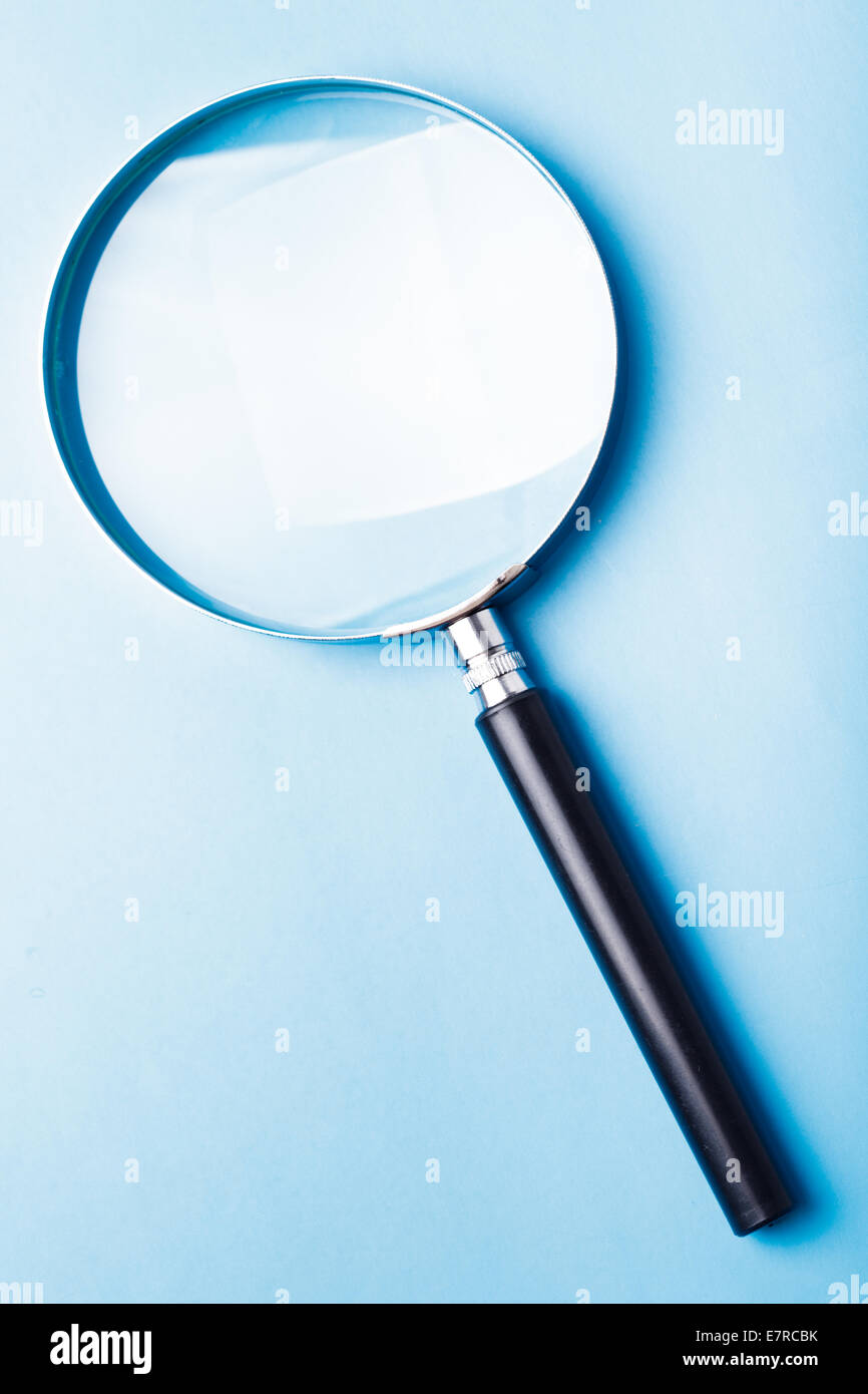 Glass magnifier closeup on a blue background Stock Photo - Alamy
