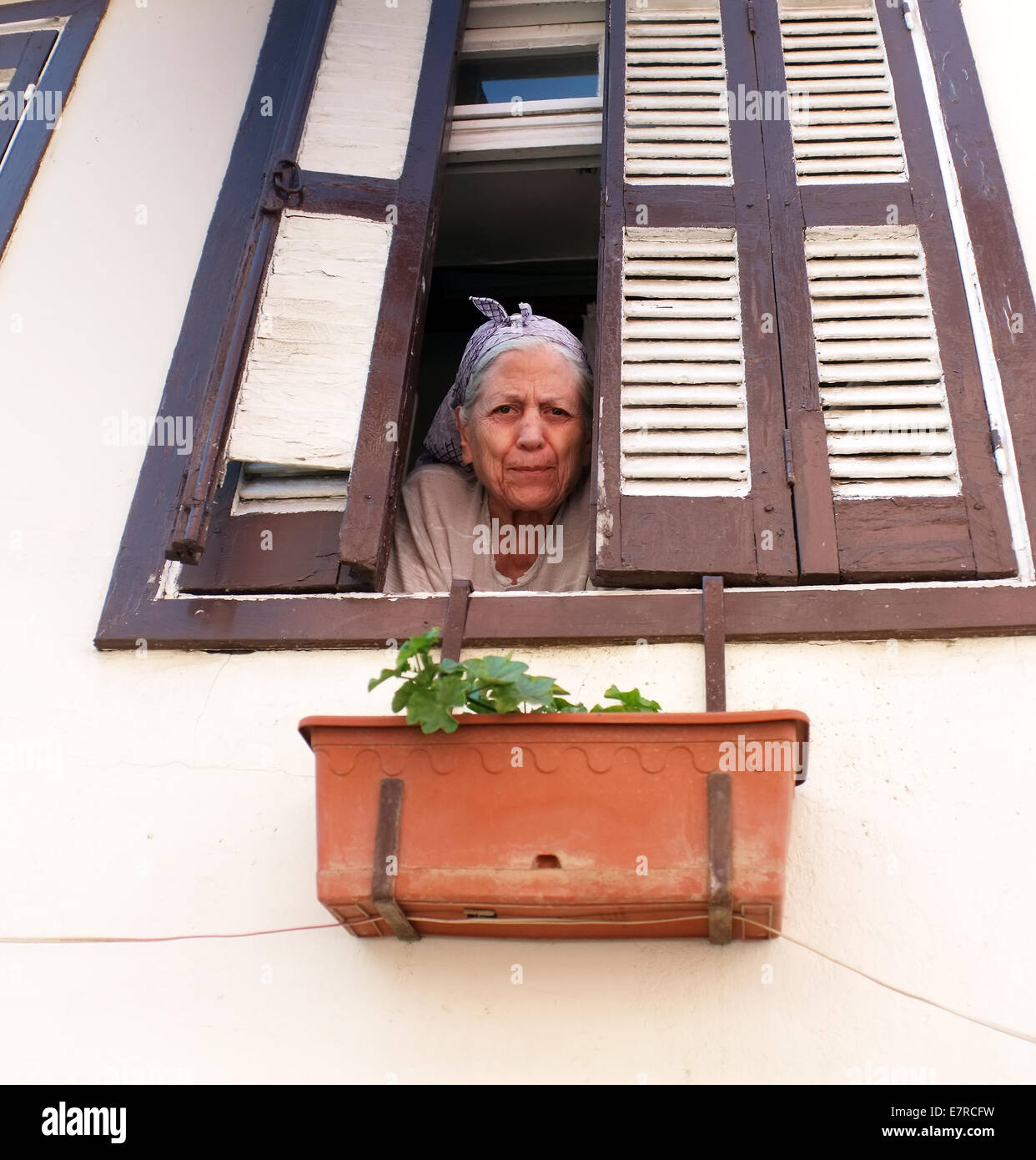 Elderly woman looks through window Stock Photo - Alamy