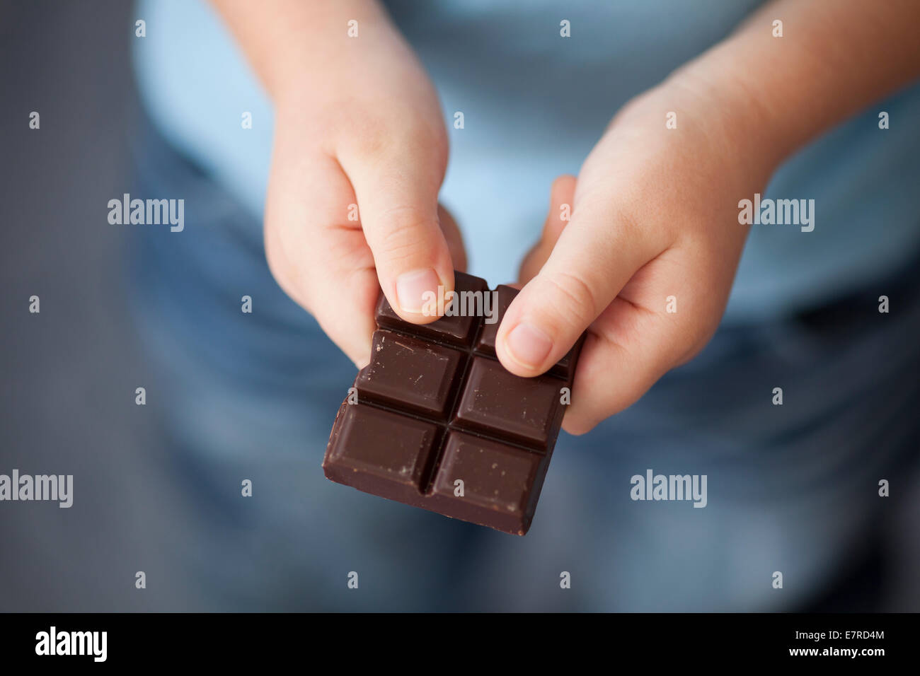 Broken piece of dark chocolate in child's hands Stock Photo - Alamy