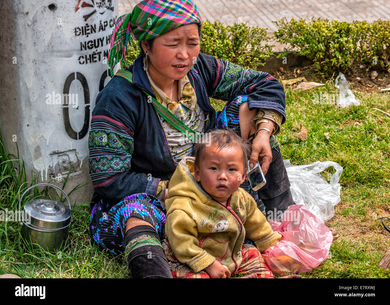 Hmong mother and child sitting on the side of the road with cell phone ...