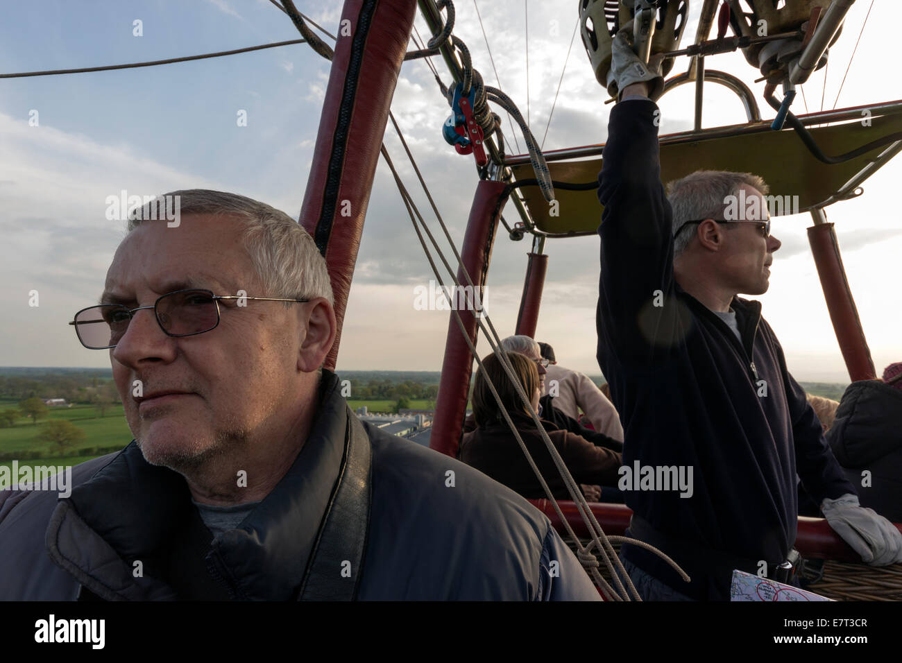 Pilot steering a hot air balloon with passengers enjoying the view ...