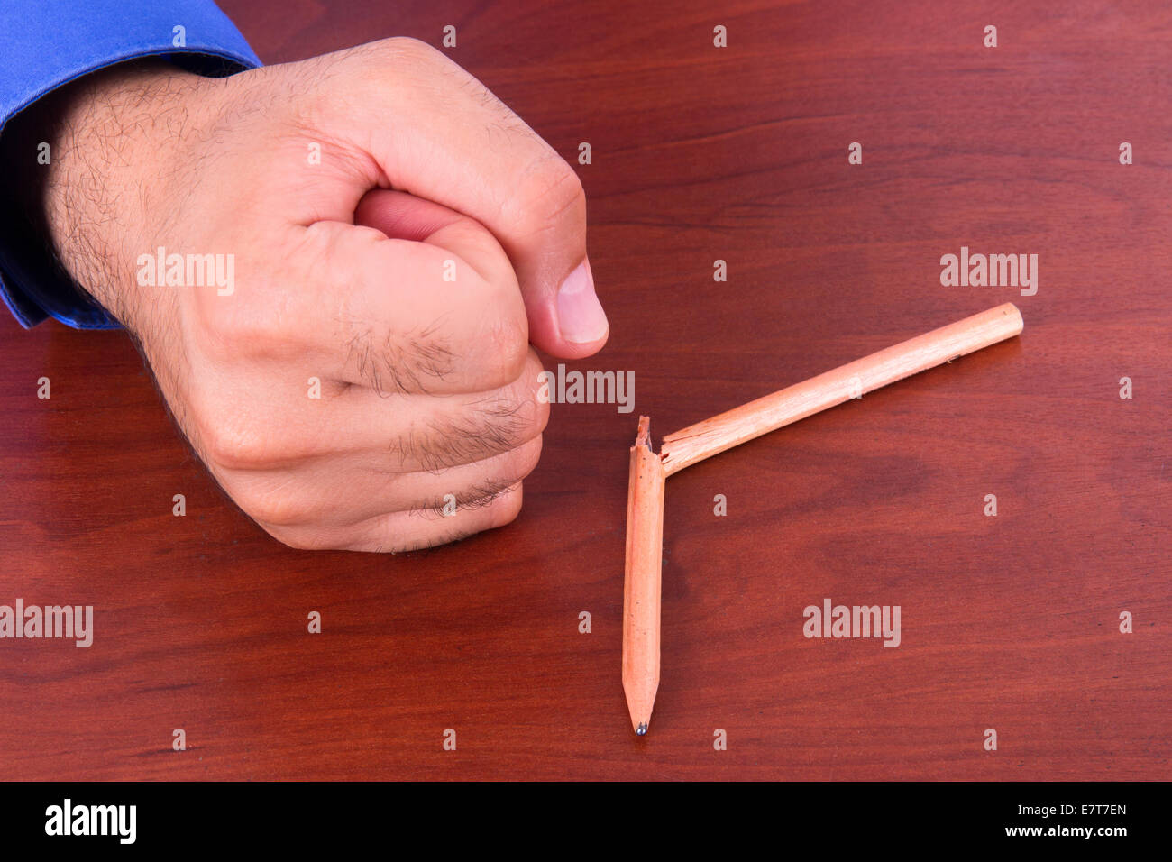 Angry businessman hand as punch and broken pencil on wooden table Stock ...