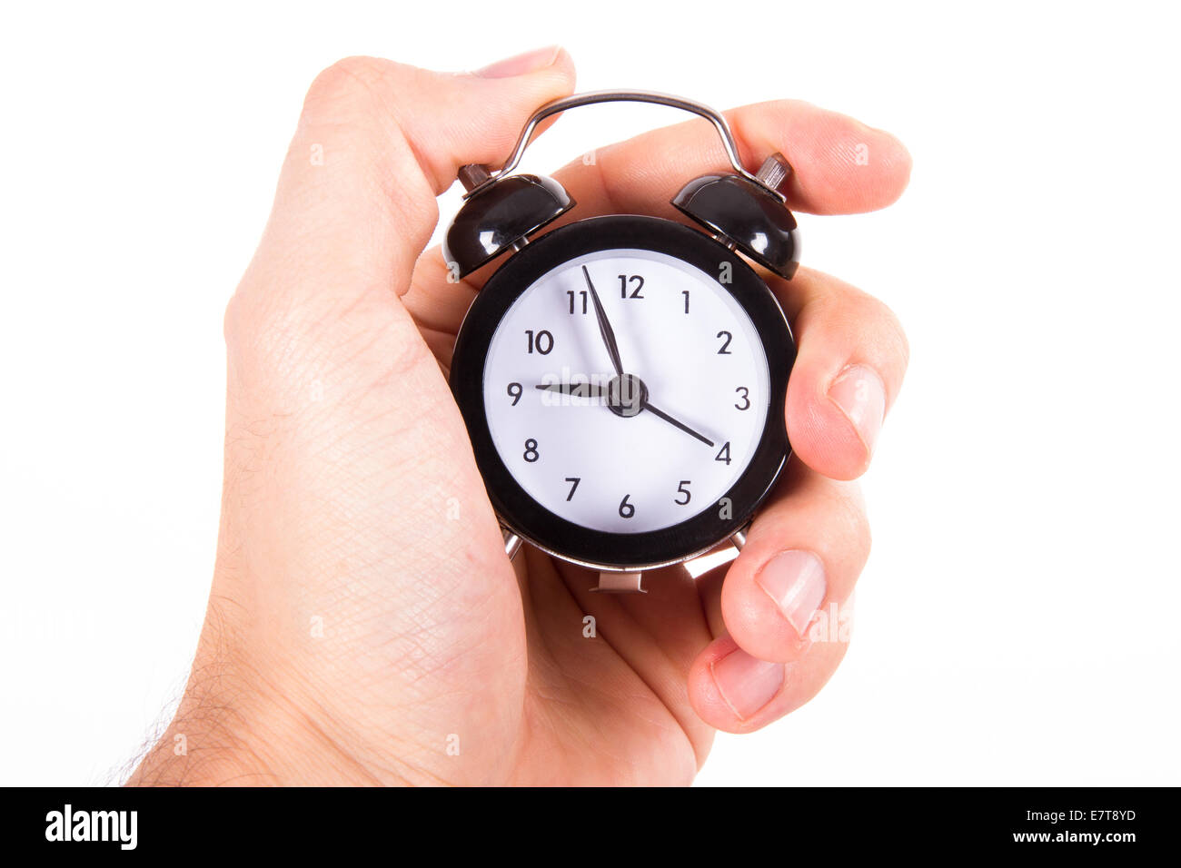 Hand holding old style fashioned alarm clock with black frame, isolated ...