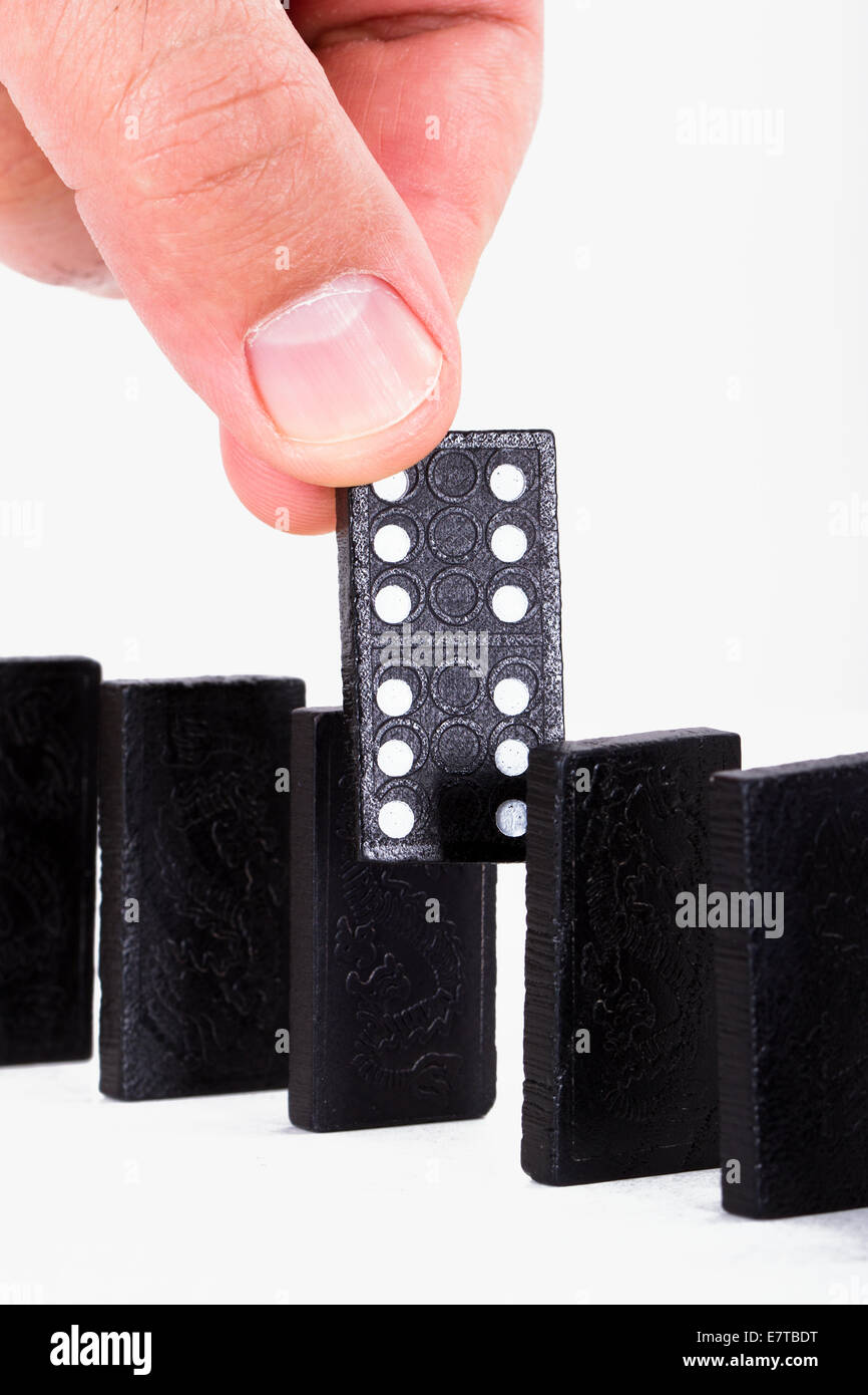 Hand holding black domino and building a line from dominoes, isolated ...
