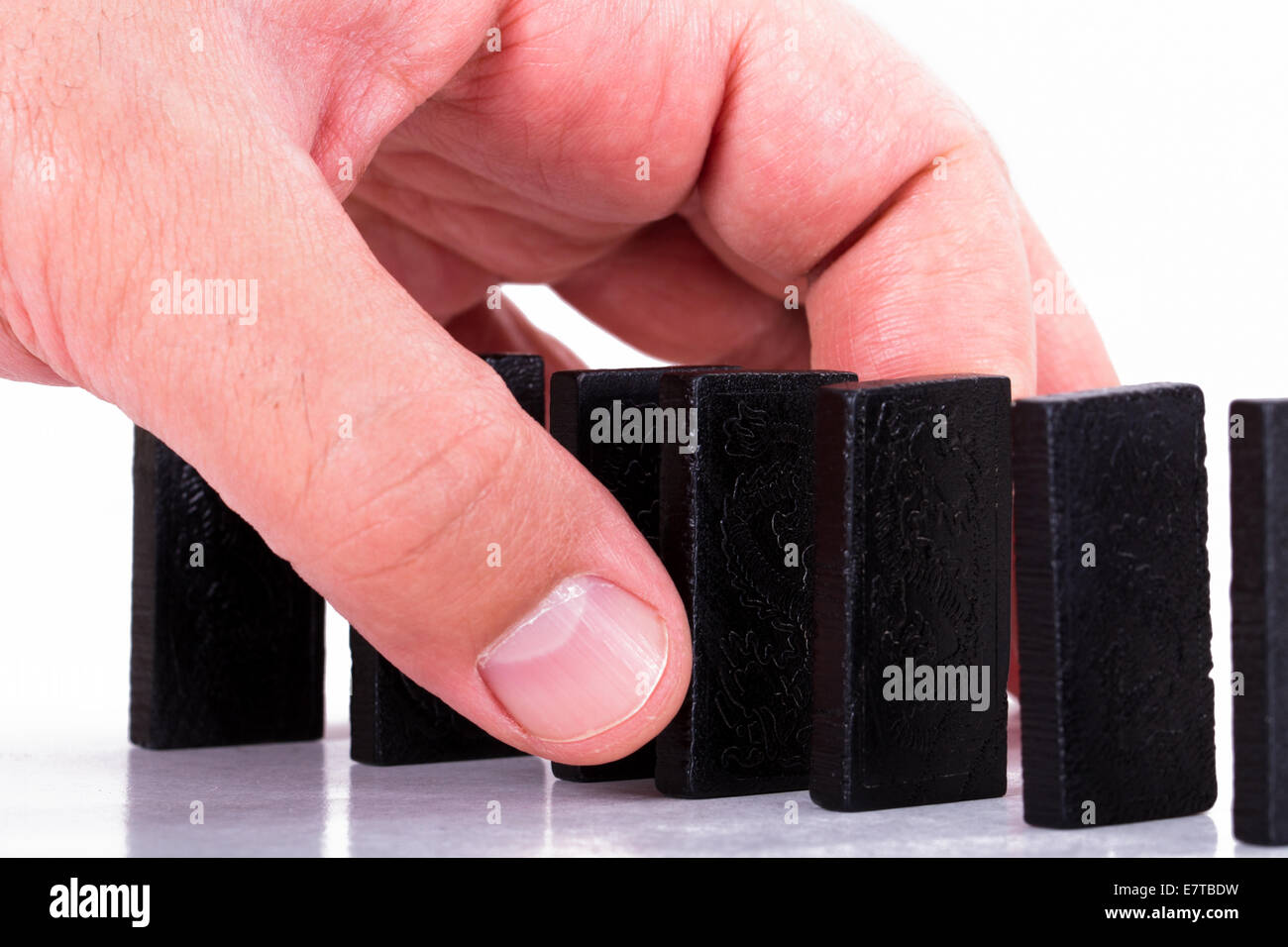 Hand holding black domino and building a line from dominoes, isolated ...