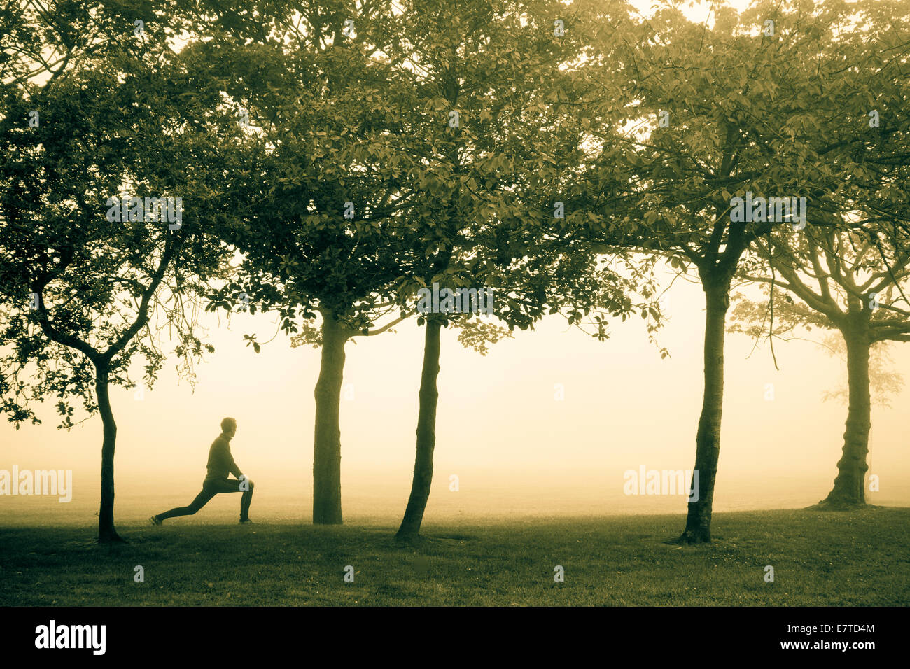 Male jogger stretching in fog Stock Photo - Alamy