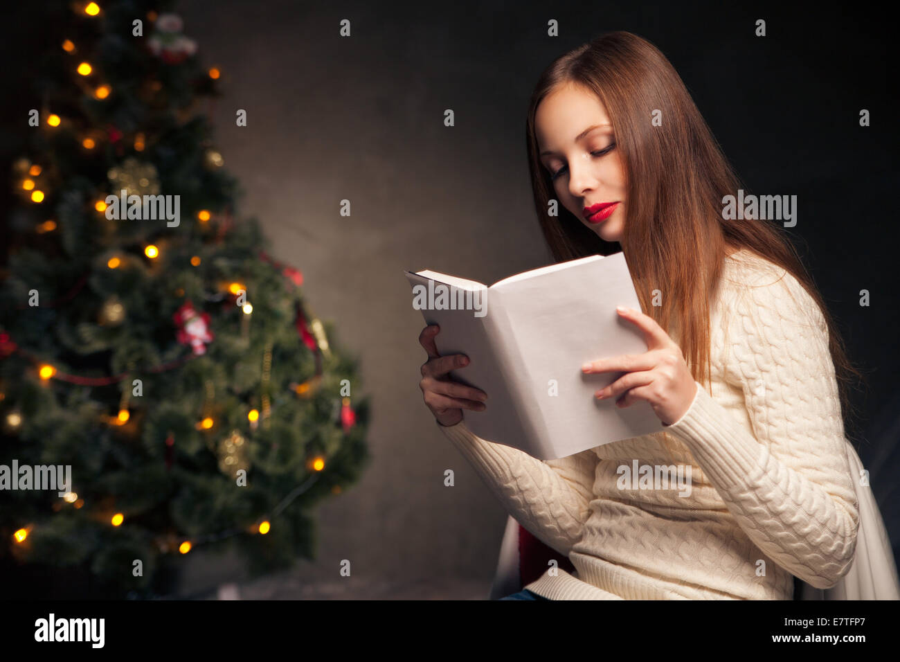 Woman in front of Christmas tree reading book Stock Photo - Alamy