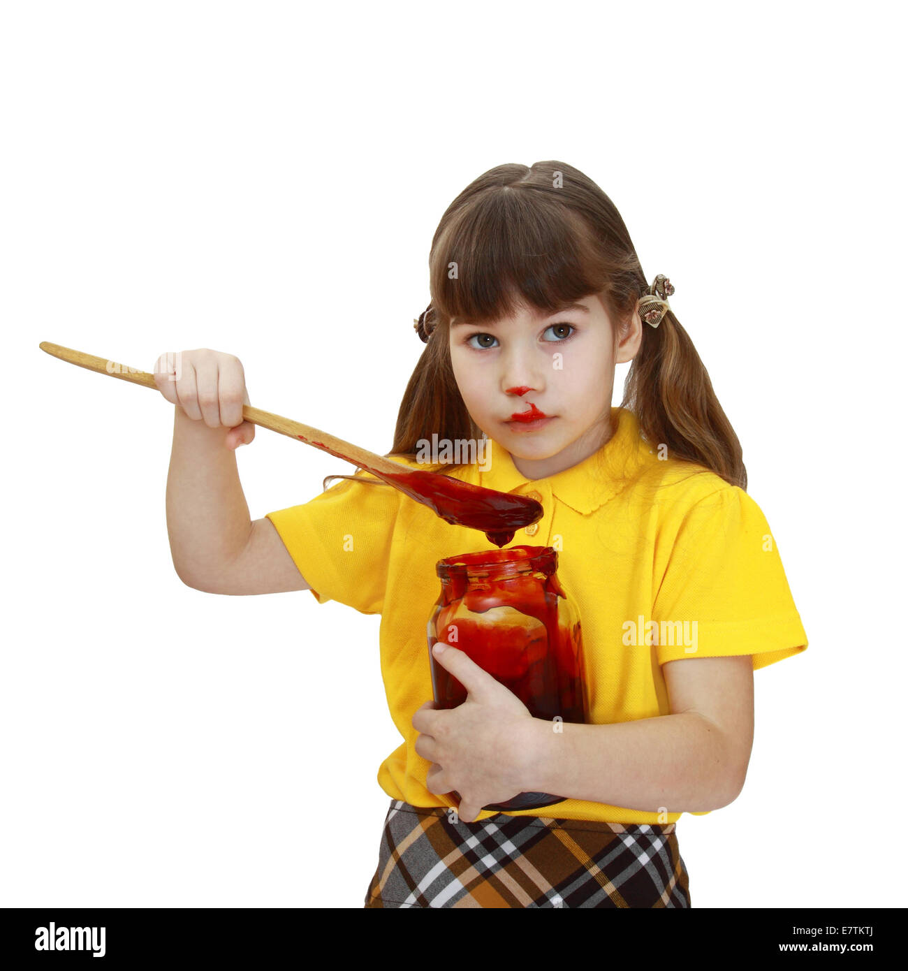 Girl with guilty facial expression and with jar of jam and big wooden ...