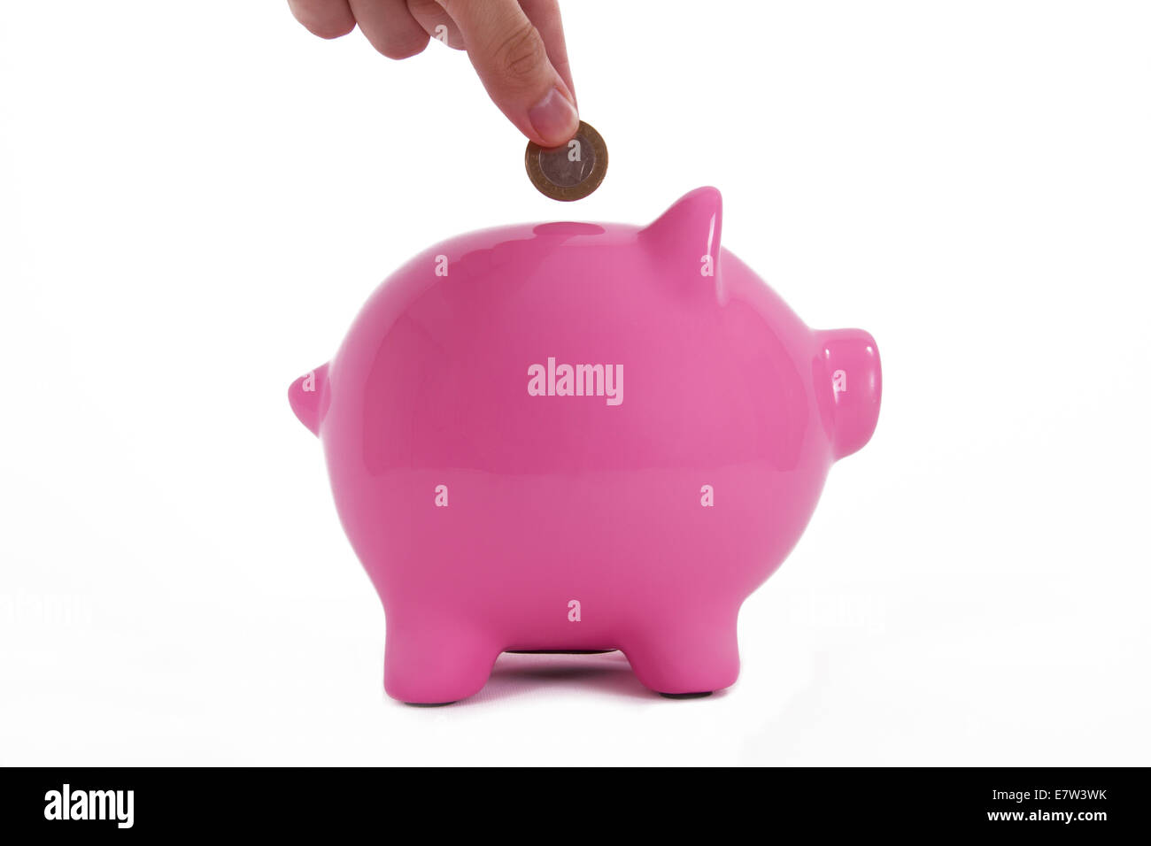 Coin holding by a human hand, fingers and pink piggy bank standing ...
