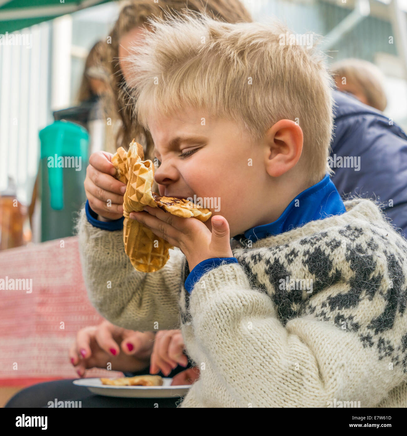 Young boy eating a waffle. Annual end of the summer festival in ...