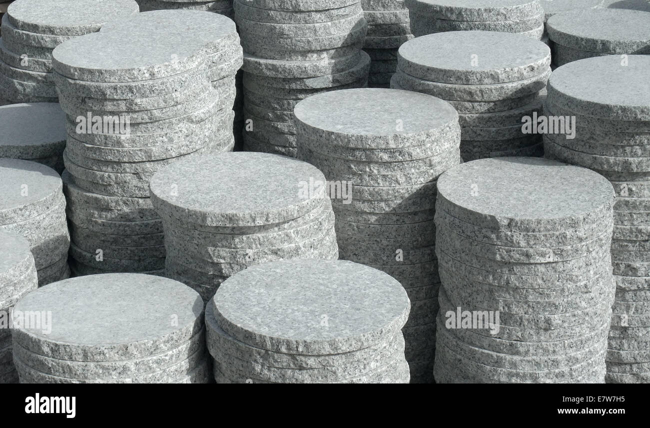 lots of stacked round grey granite slabs in sunny ambiance Stock Photo ...