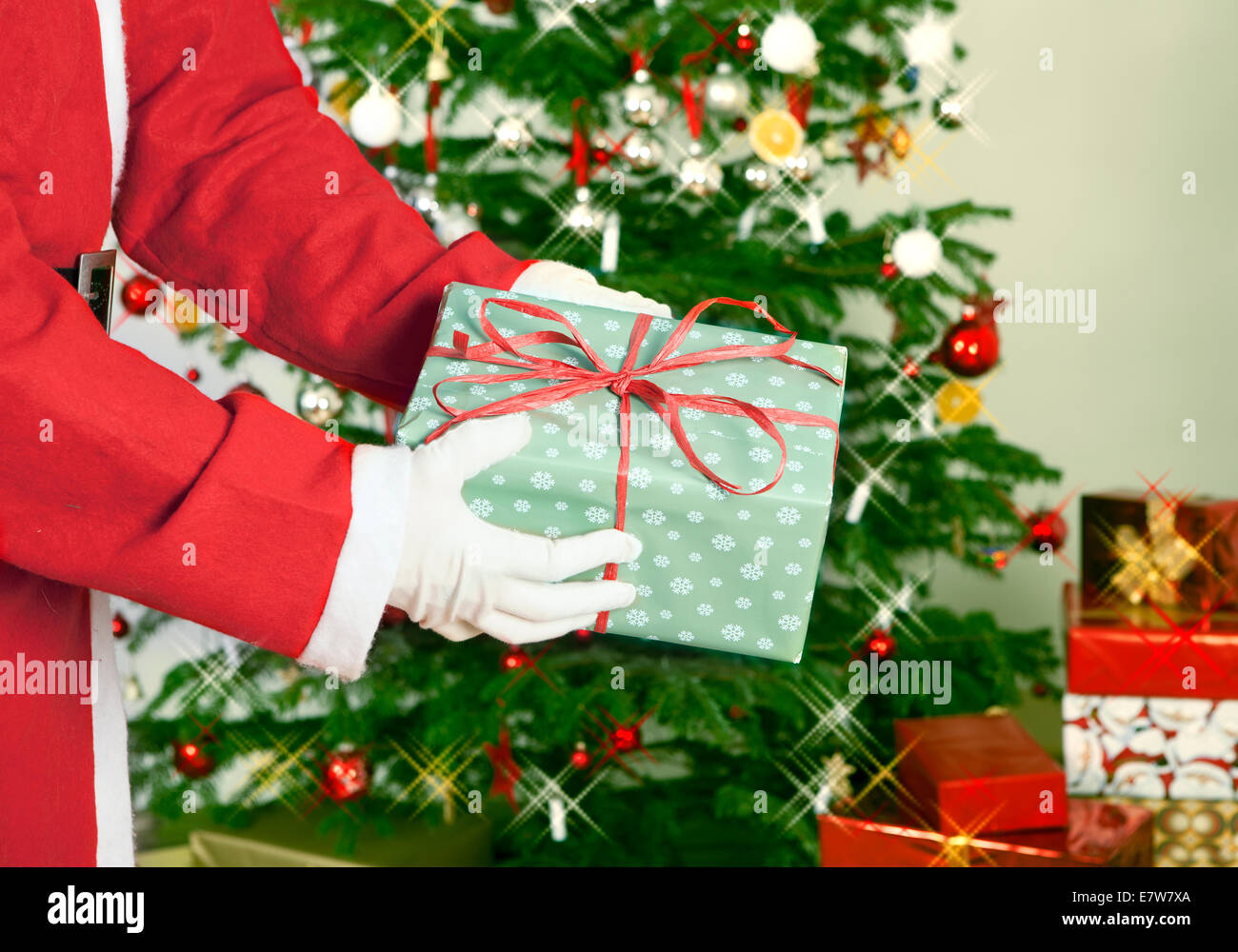 Santa Claus with a gift in hand in front of a Christmas tree Stock ...