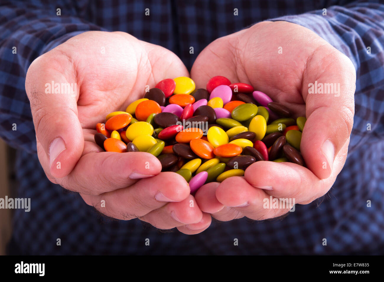 Hand reaching little colorful sugar candies, isolated on white ...