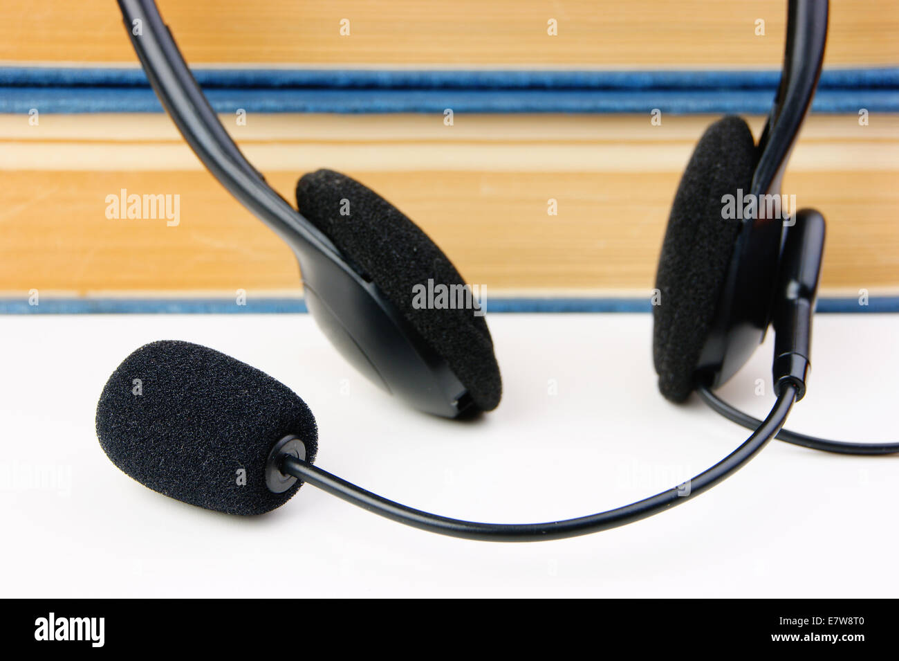 Headphones with a microphone and a stack of books on white background ...
