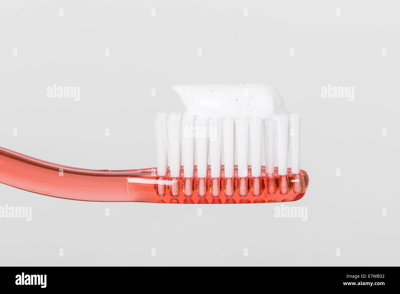 Side view of toothbrush with red plastic body, toothpaste on brushed ...