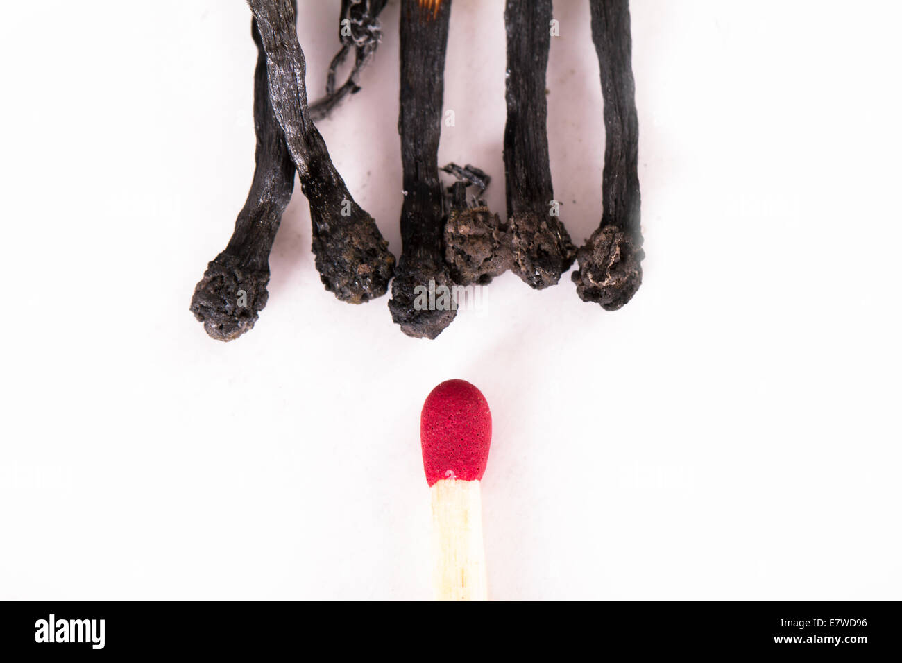 Single red headed match standing out against group of used, burnt ...