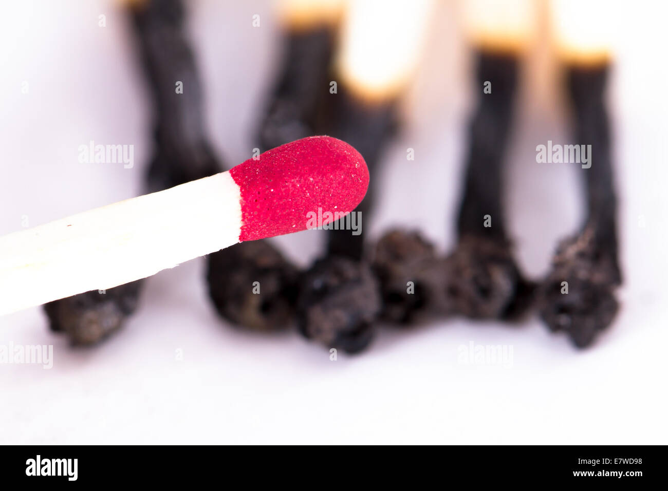 Single red headed match standing out against group of used, burnt ...