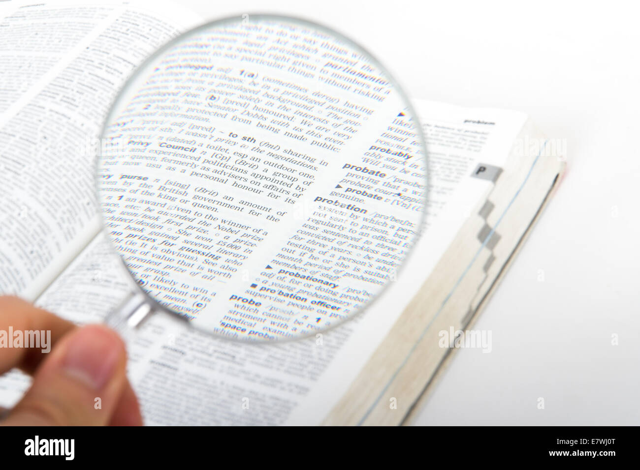 Hand holding magnifying glass, examining dictionary page, isolated on ...