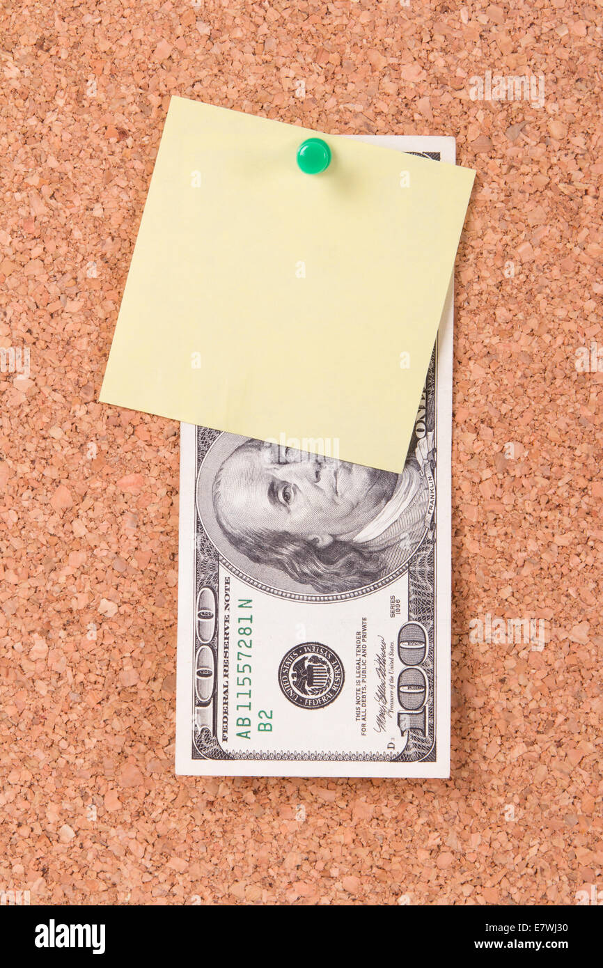 One hundred dollar bill and blank, empty yellow sticky post affixed to ...