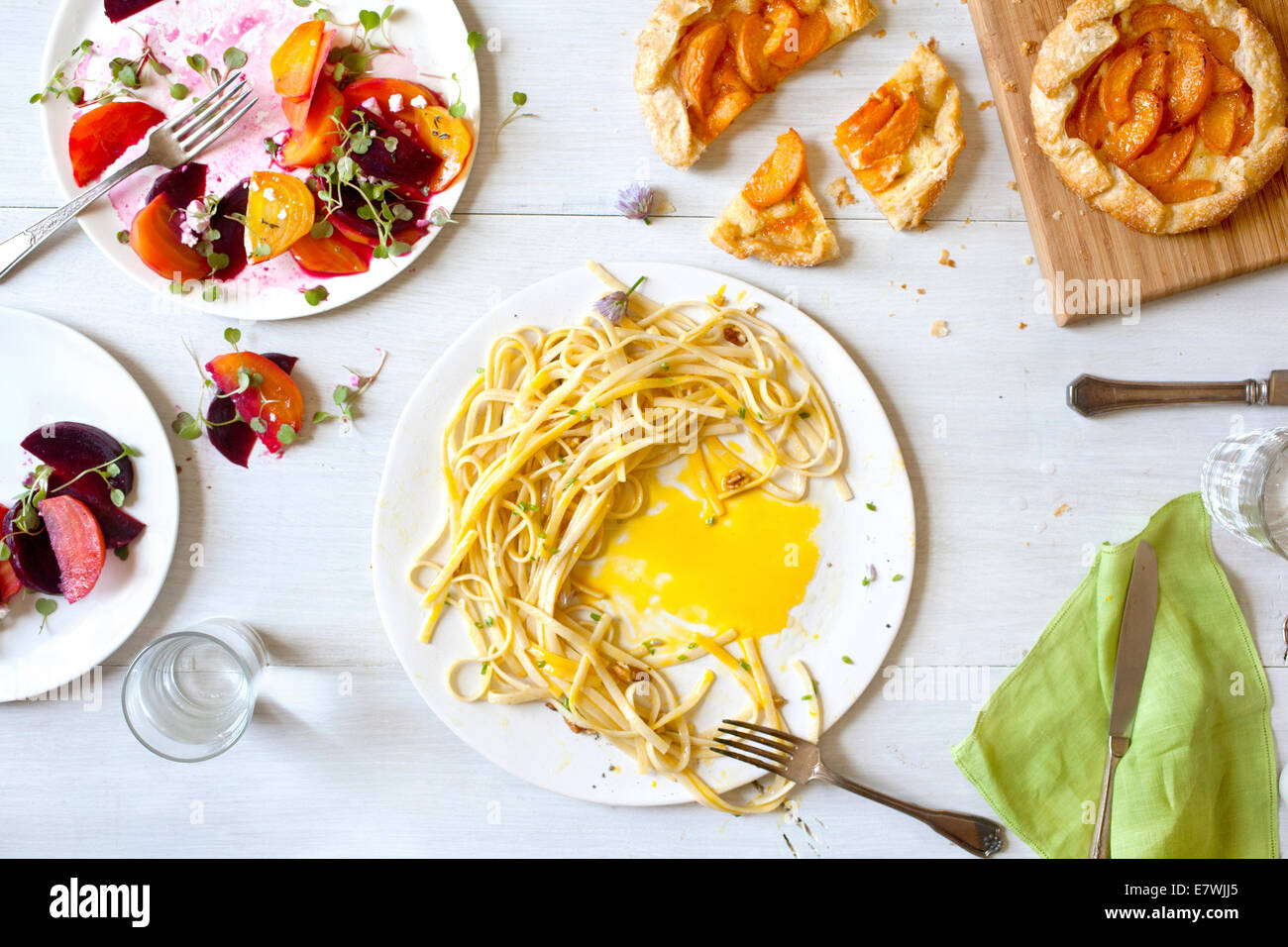 Messy spaghetti, beet salad, and apricot tart leftovers Stock Photo - Alamy