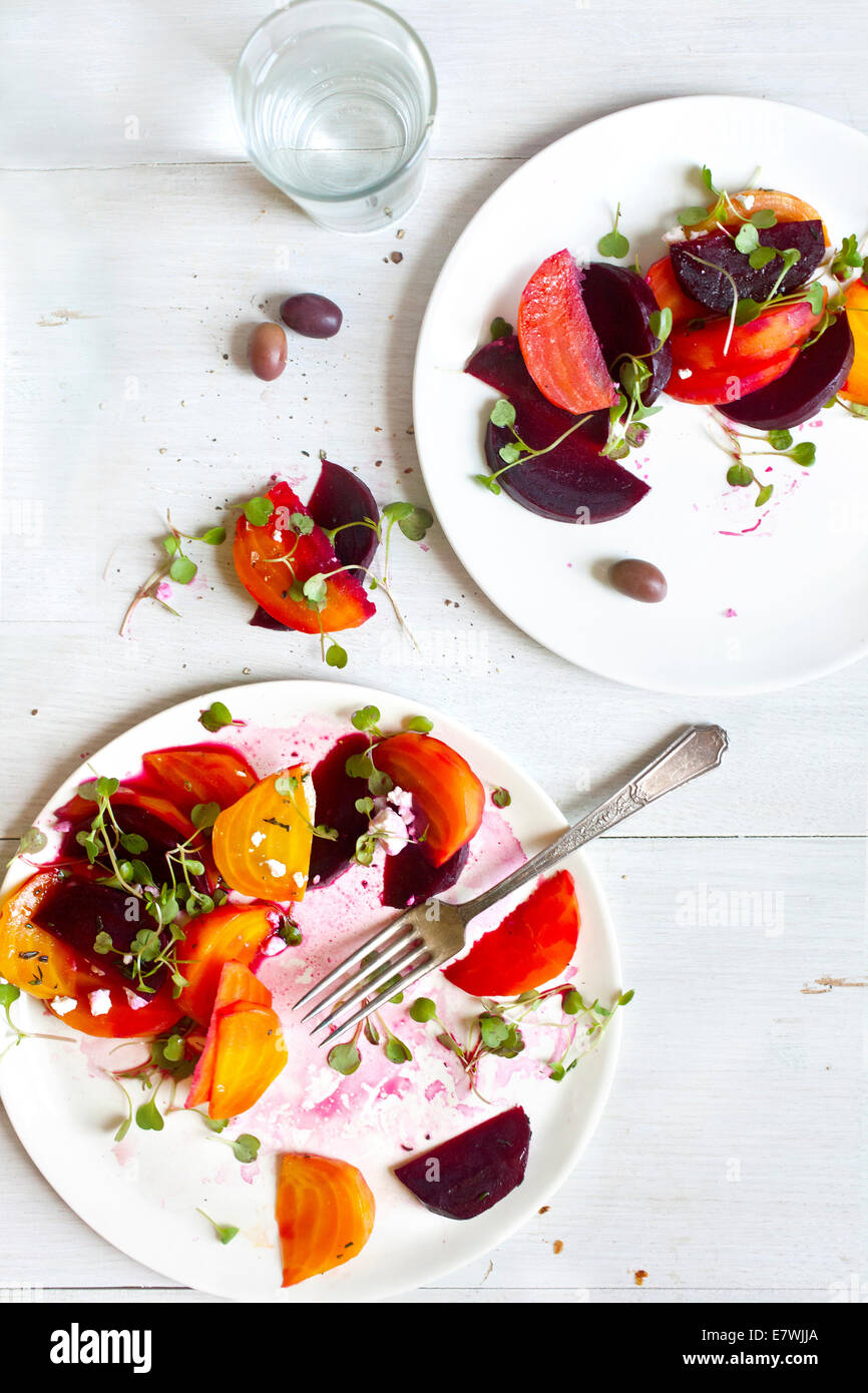 Colorful beet salad plated on white plate and backdrop, half eaten and ...