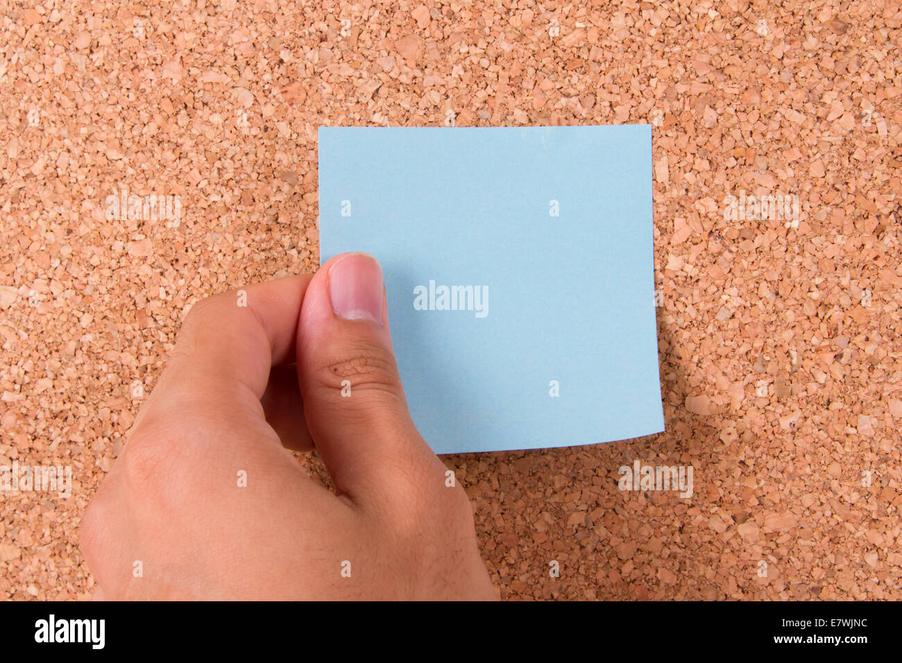Hand and blank, blue sticky post it note for your message on cork ...