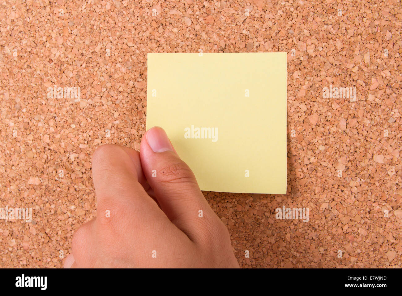 Hand and blank, blue sticky post it note for your message on cork ...