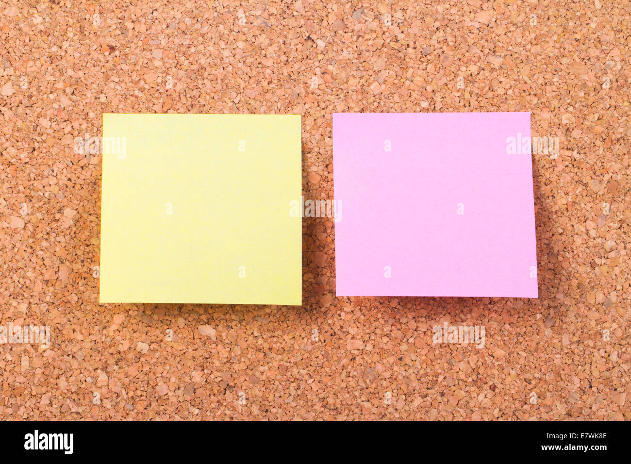 Blank, empty, yellow and pink sticky post it notes on cork bulletin ...