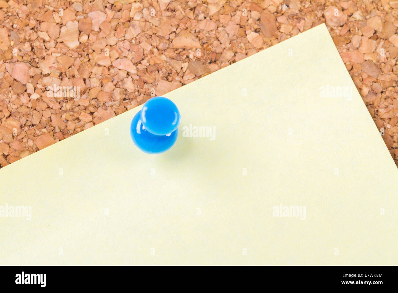 Blank, empty yellow sticky post it note with blue pin on cork bulletin ...
