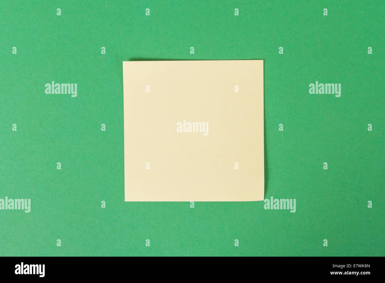 Single, blank, empty, yellow sticky post it note on green background ...