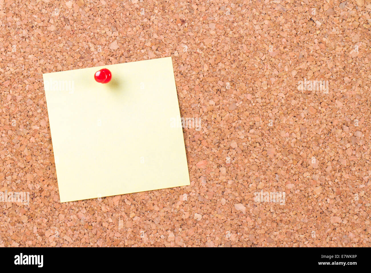 Blank, empty, yellow sticky post it pinned on cork bulletin board with ...