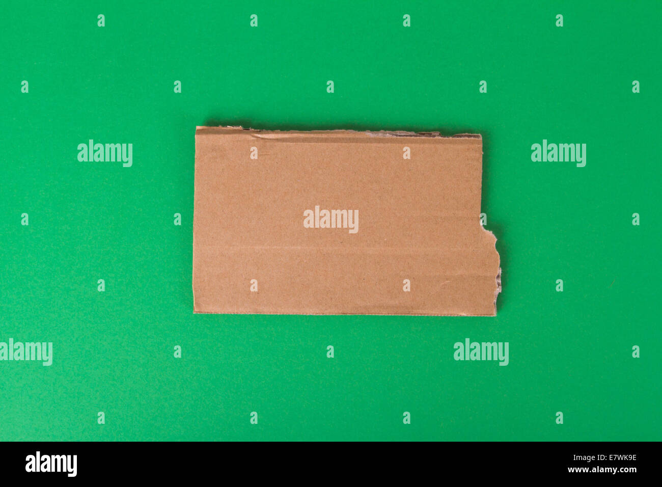 Teared, ripped cardboard on green background Stock Photo - Alamy