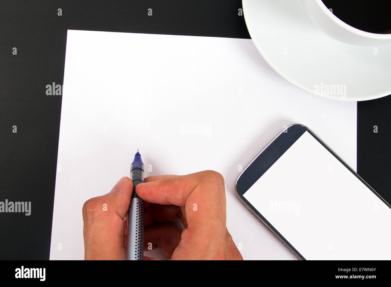 Hand writing blank, white paper, smart phone with empty screen, ceramic ...