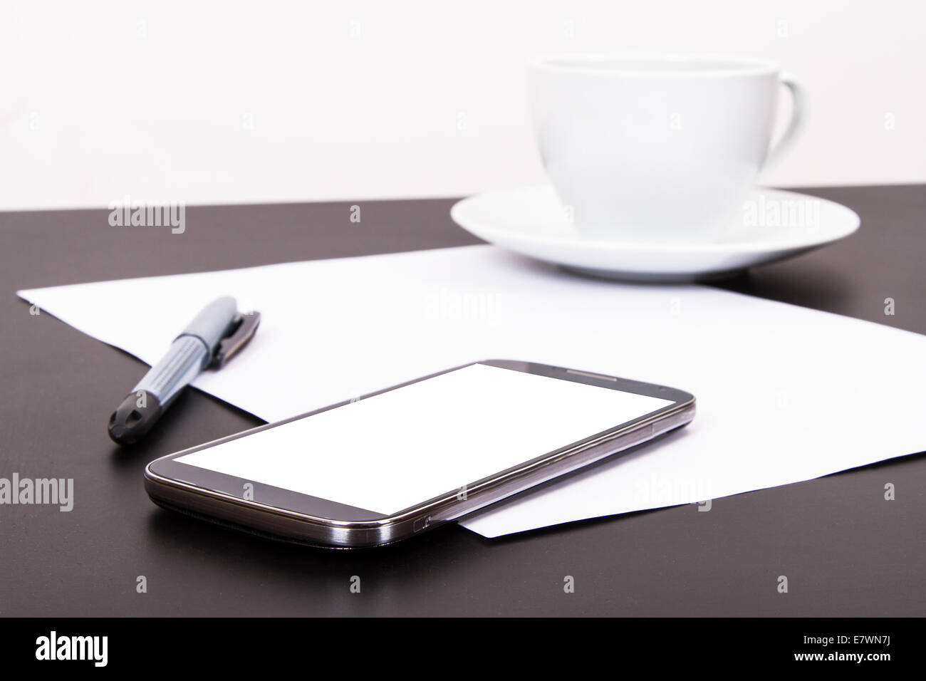 Smart phone with blank, white screen, ceramic coffee cup, pen and empty ...