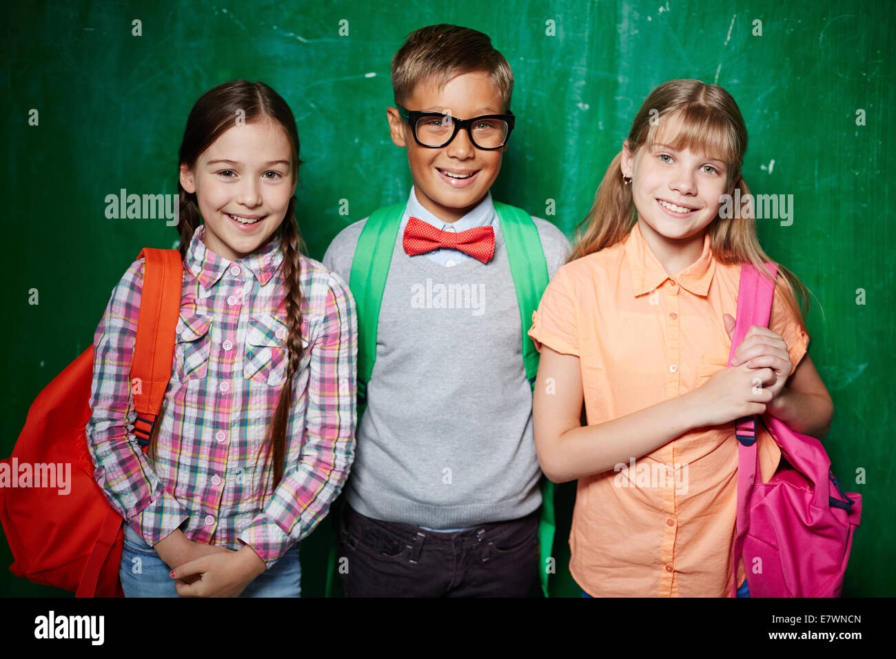 Happy schoolkids standing by the blackboard and looking at camera Stock ...